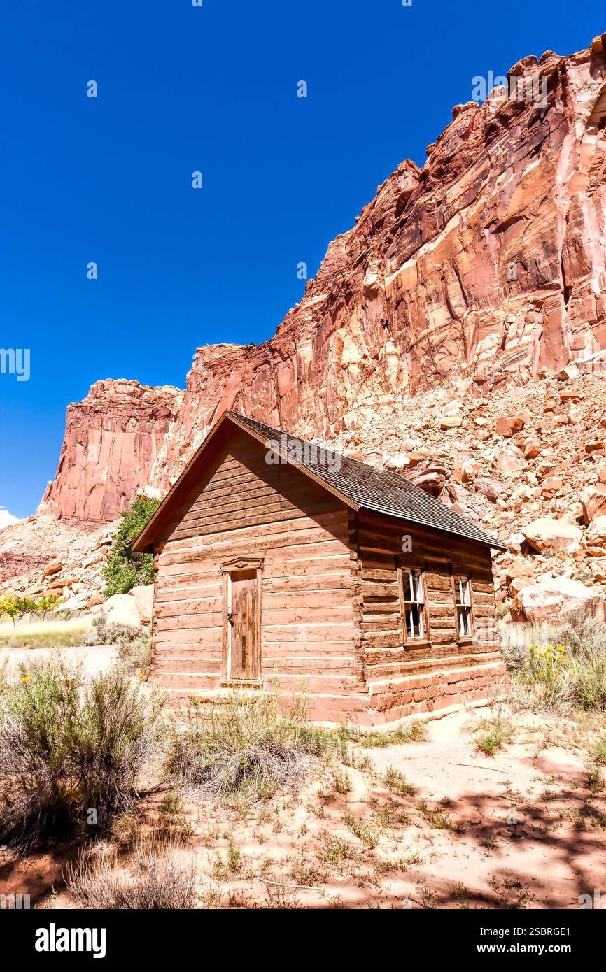 A small log cabin is in the desert. The cabin is surrounded by a rocky ...