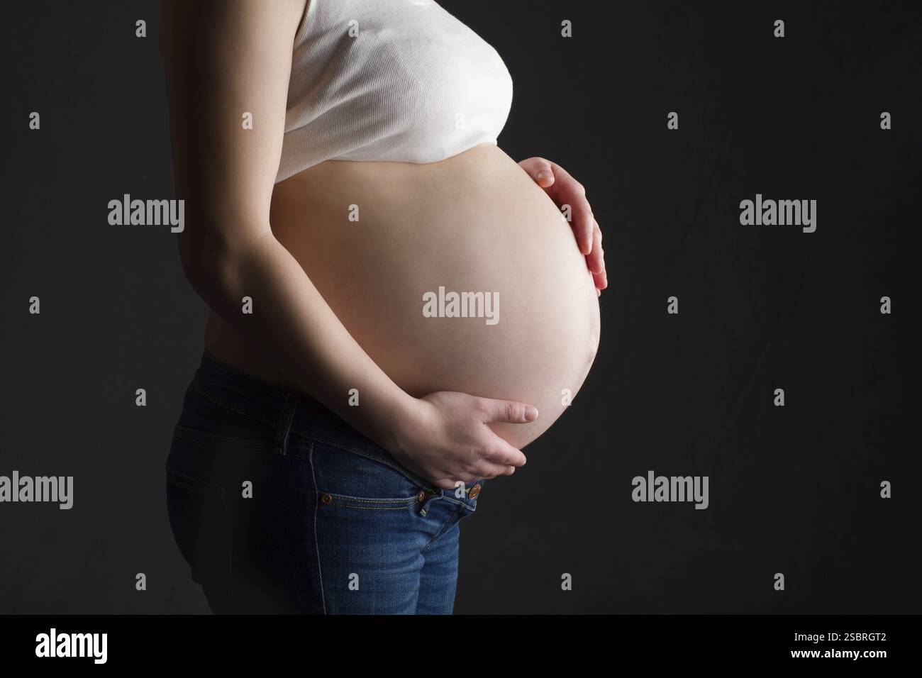 Pregnant woman, expectant mother on black background, close-up of ...