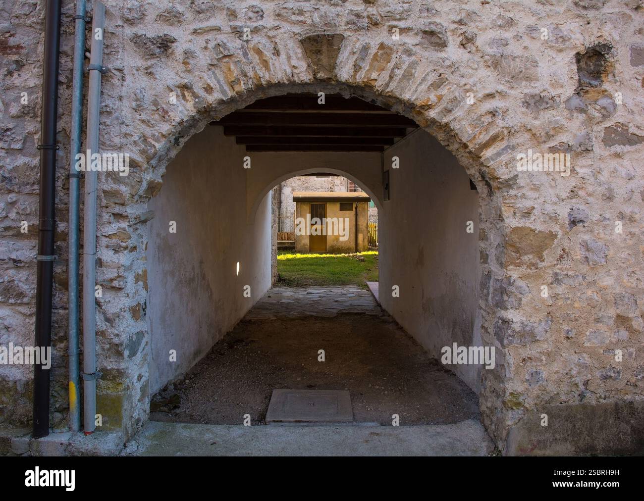 An arched passageway from a road to the back of some houses in the ...