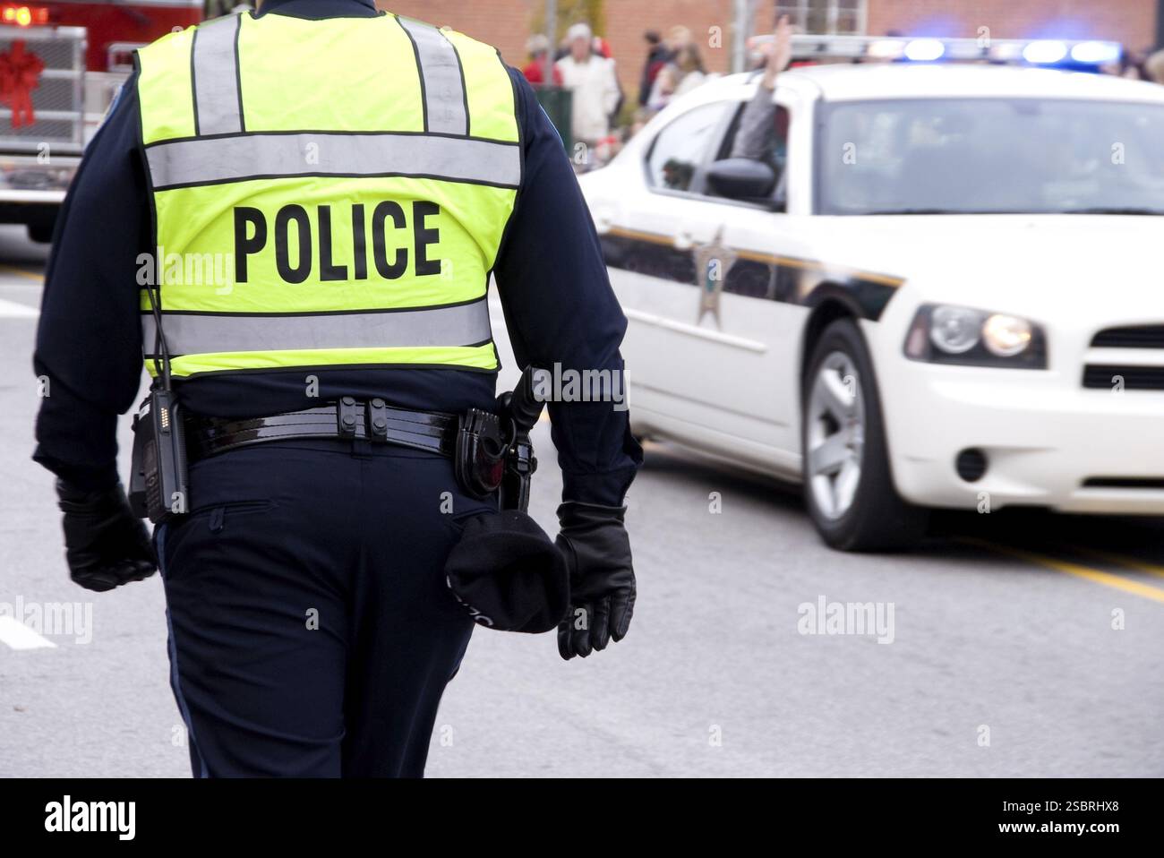 AQ policeman walking by a patrol car on the street Stock Photo - Alamy