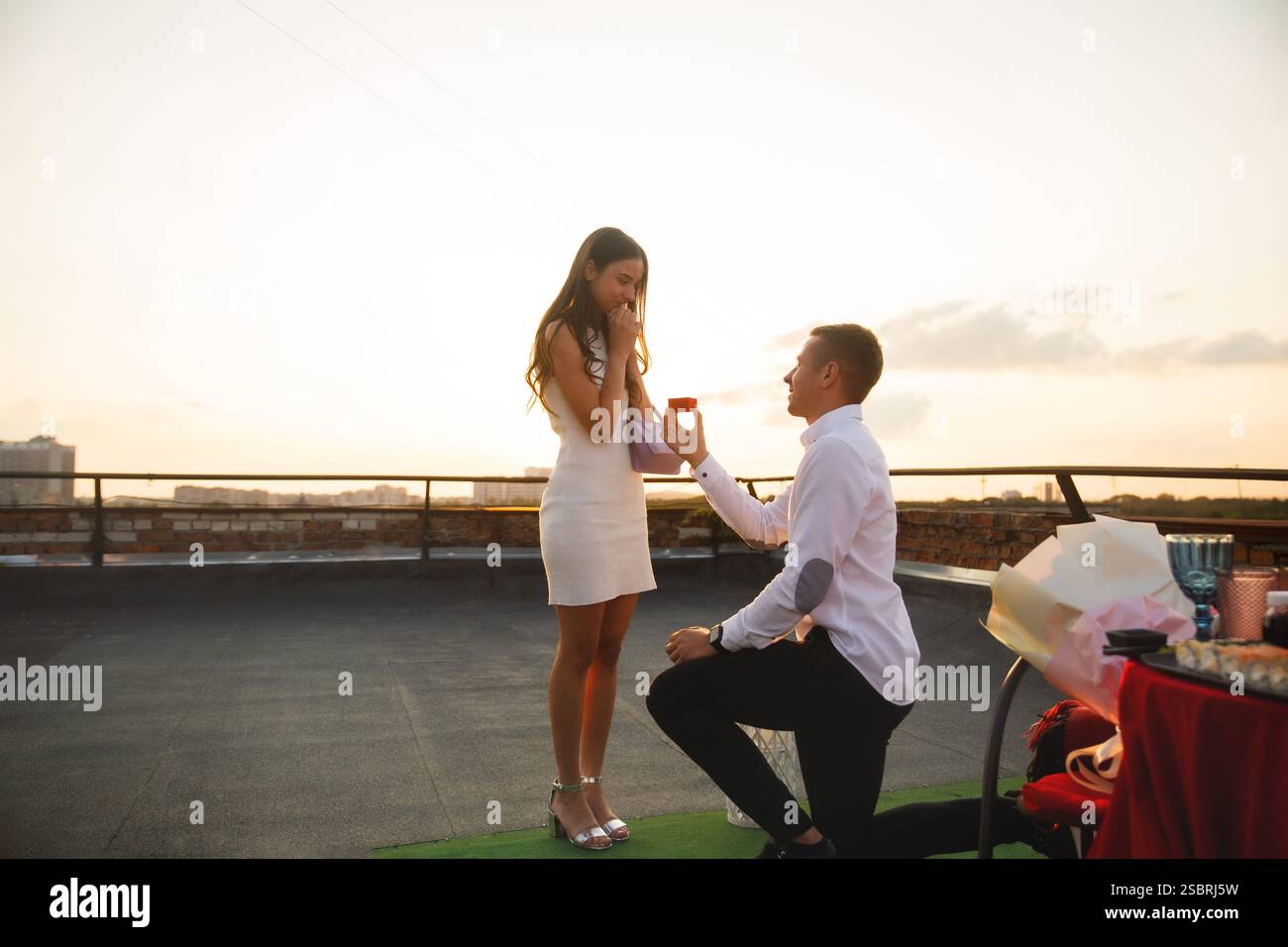 A couple shares an intimate moment on a rooftop during sunset, where ...
