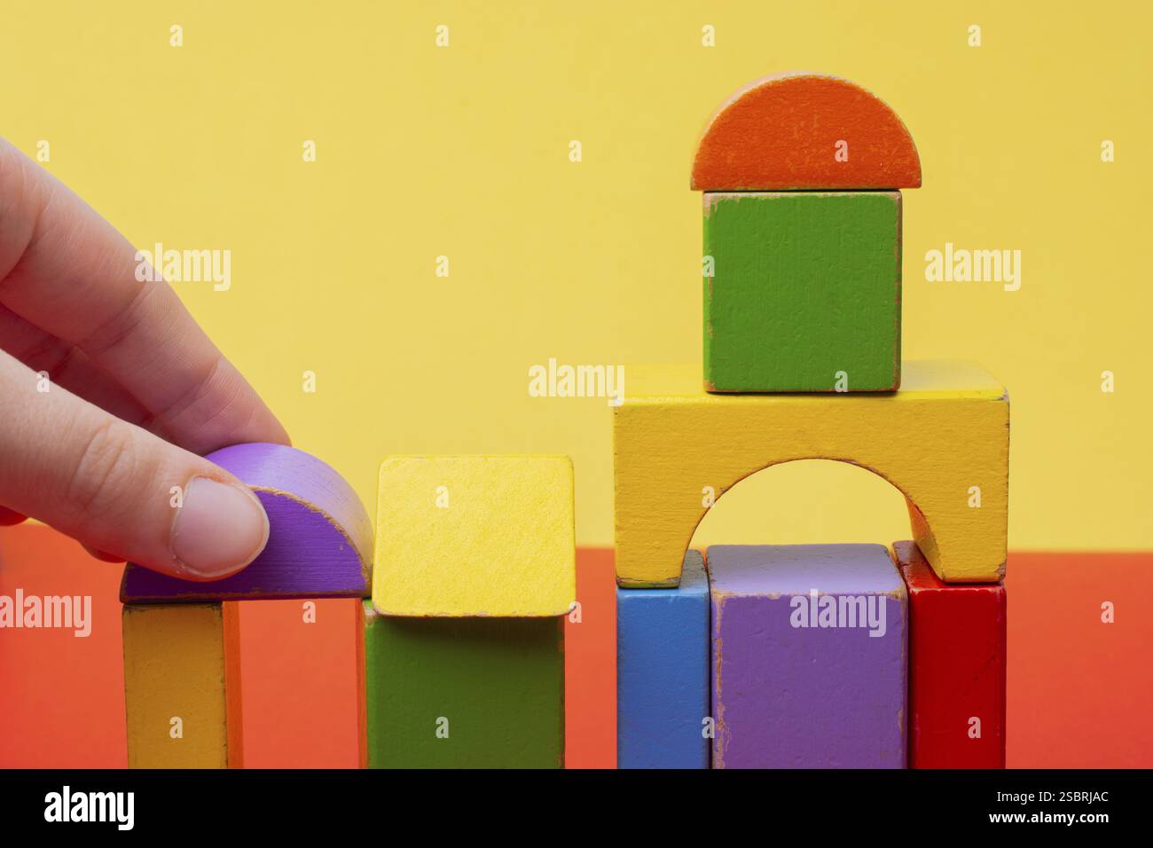 Hand building tower with colorful building blocks Stock Photo - Alamy