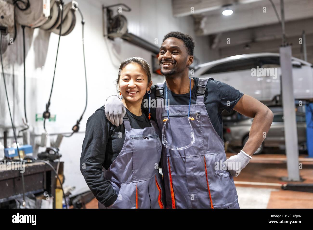 Two cheerful mechanics are posing together in a professional auto ...