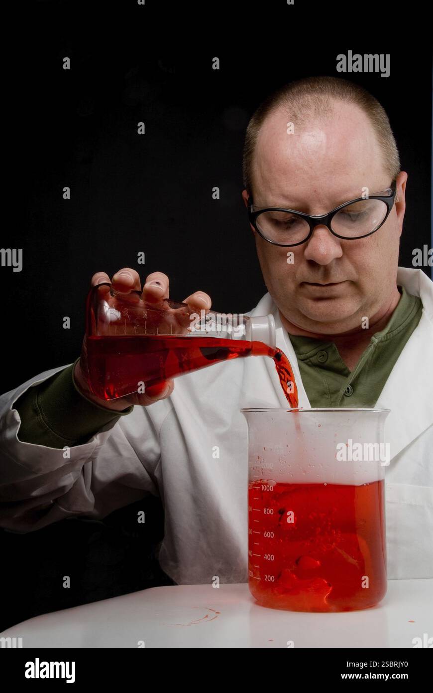 A Scientist pouring a solution into a beaker Stock Photo - Alamy
