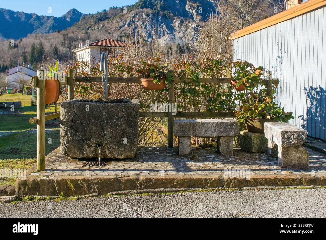 A stone drinking water fountain and benches in the historic village of ...