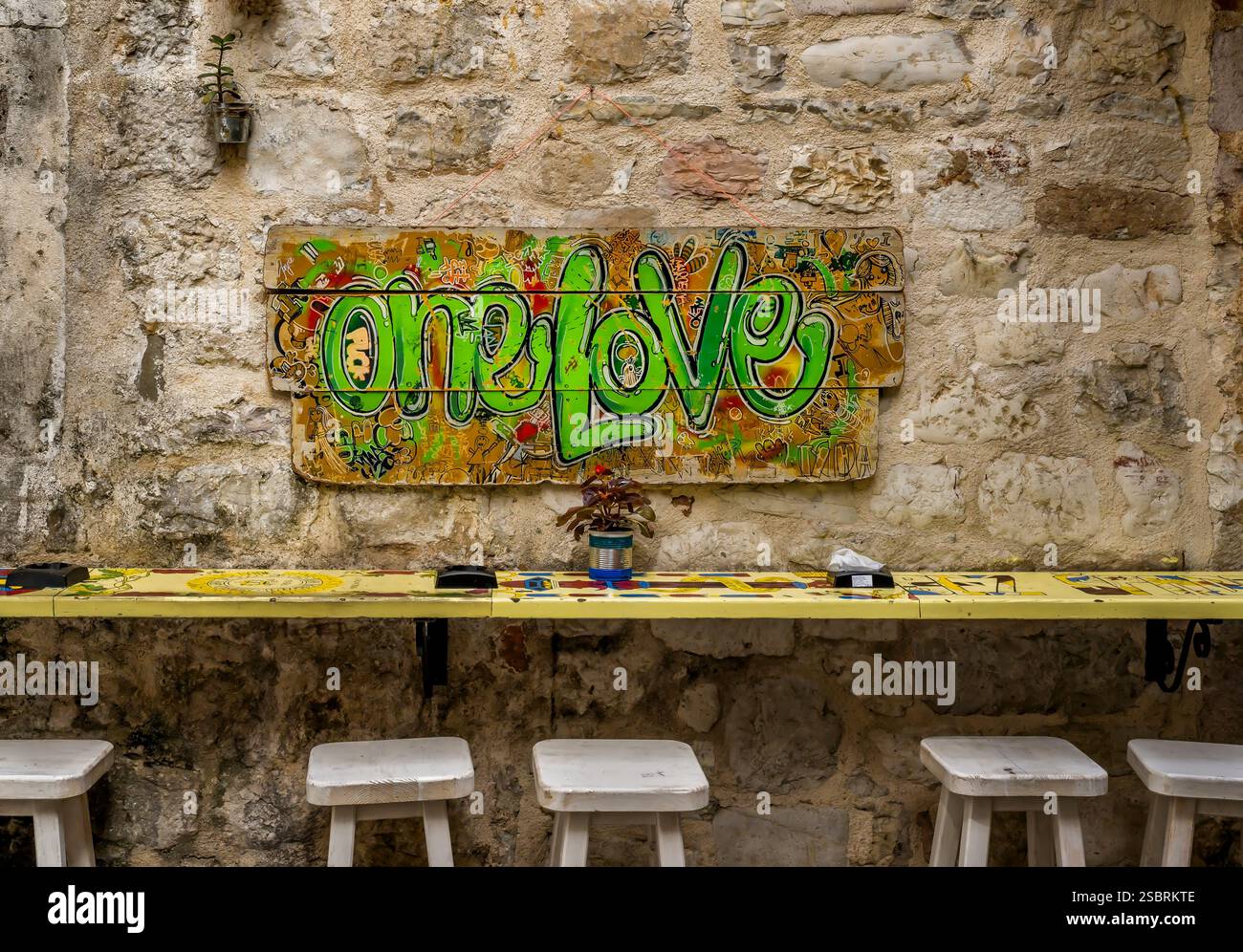 Colorful graffiti spelling 'One Love' adorned on an old, textured wall ...