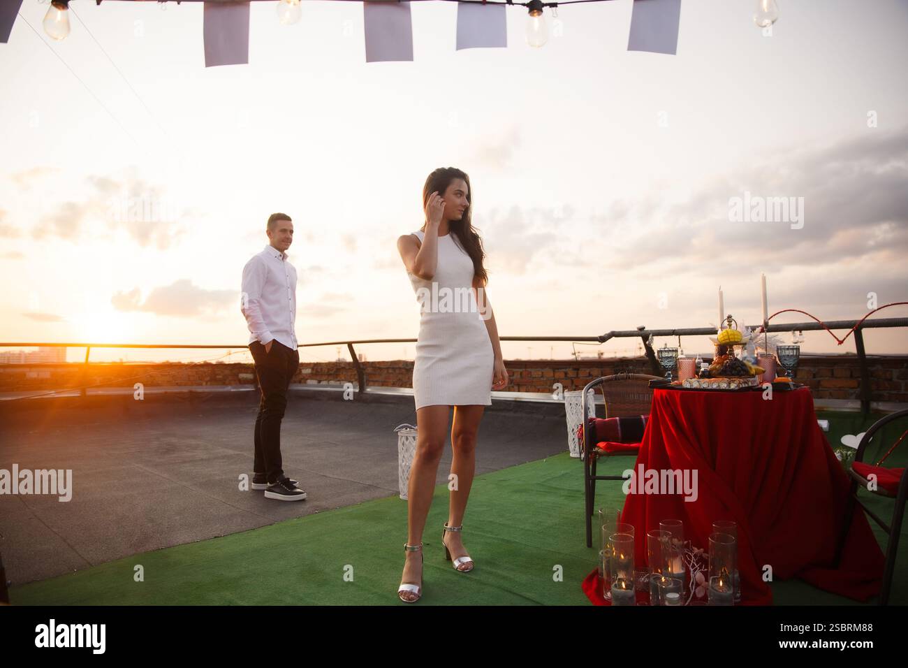Romantic rooftop sunset dinner with elegant table setting and couple ...