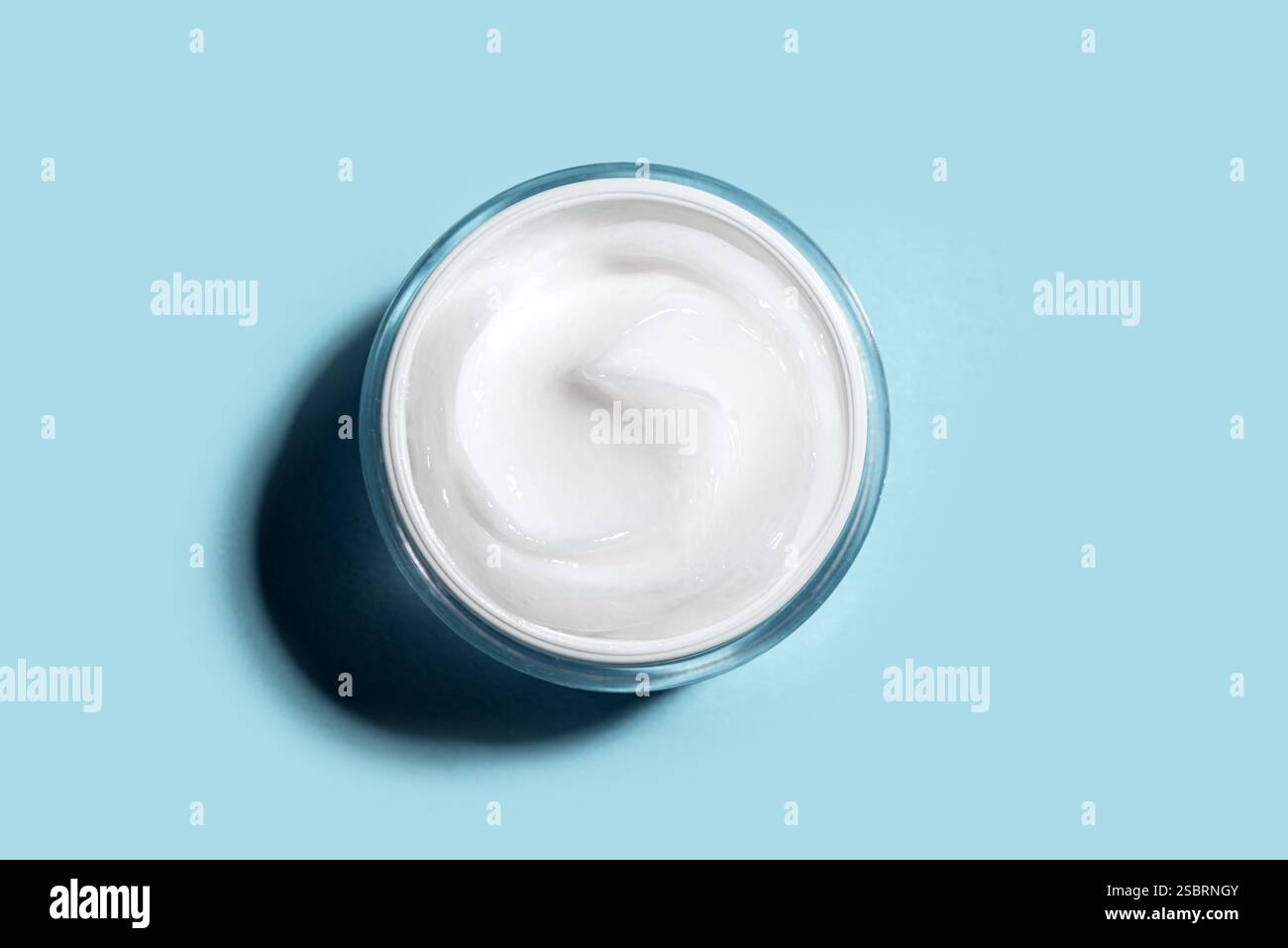 Open cosmetic cream jar on blue background, top view, copy space. Gel ...