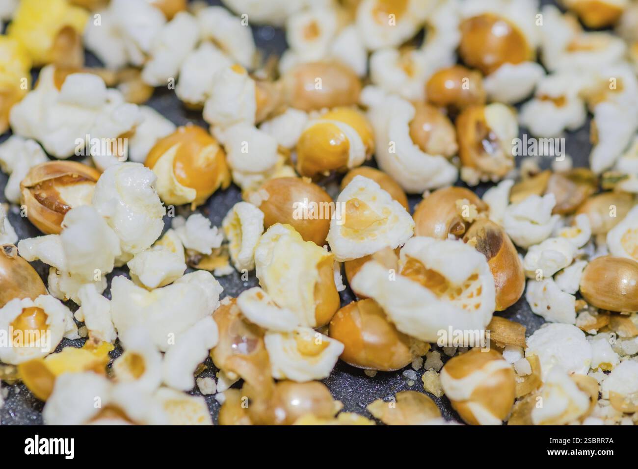 Close-up of popcorn with unpopped kernels scattered across the surface ...