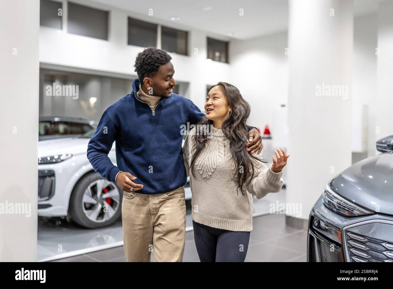 Happy multiethnic couple walking and choosing an electric car in a ...