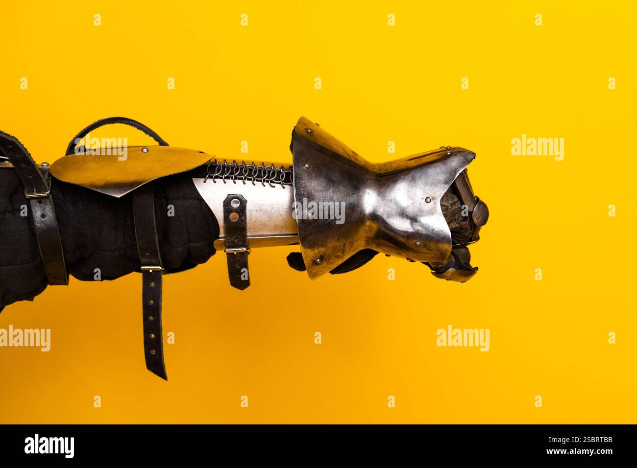 A medieval armored gauntlet extended on a vibrant yellow background ...