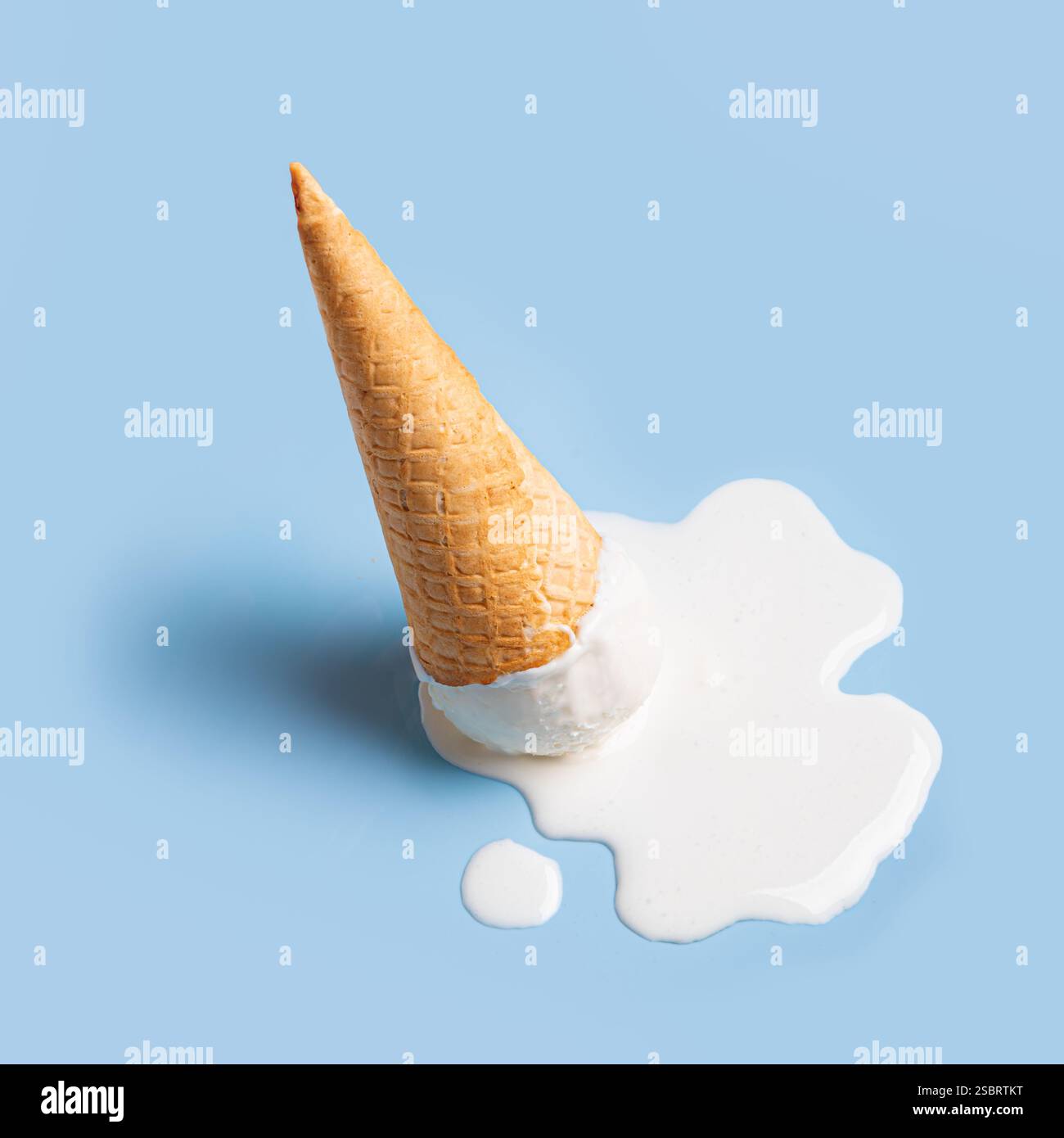 White ice cream melting and spilling from the waffle cone on pastel ...