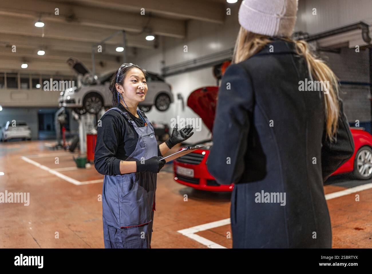 Professional female mechanic explaining car repair details to customer ...