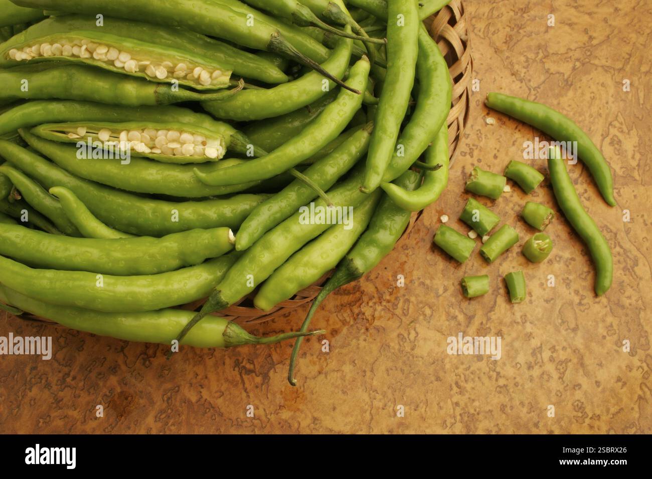 Fresh green chillies or pepper vegetable kept in cane bowl with two ...