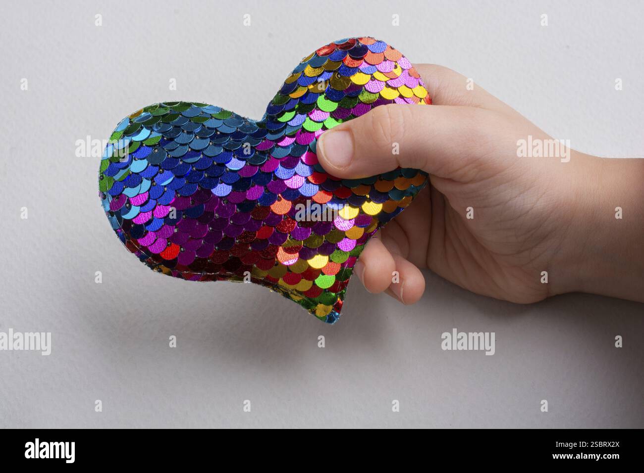 Bright multi color heart shaped object on in hsand on white background ...