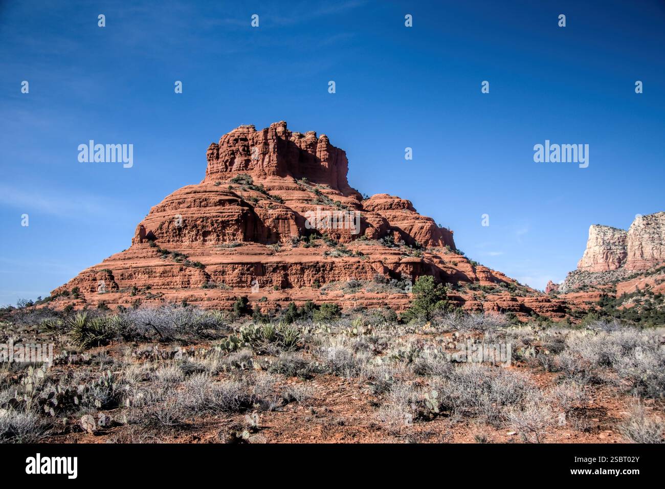A mountain with a red rock face and a blue sky. The mountain is in the ...