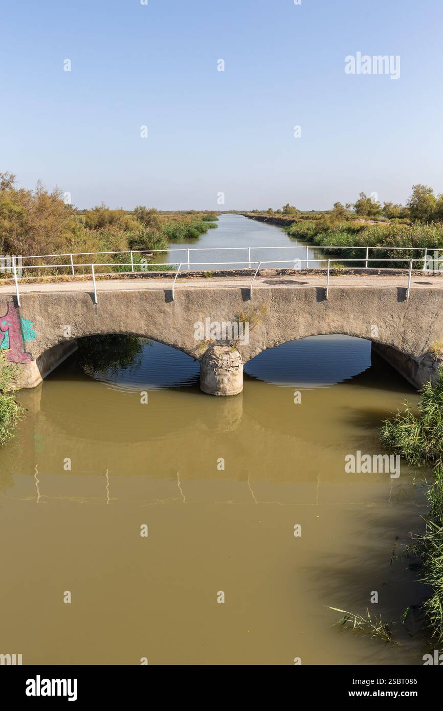 Drainage channel spanned by a bridge in the Camargue plain Stock Photo ...