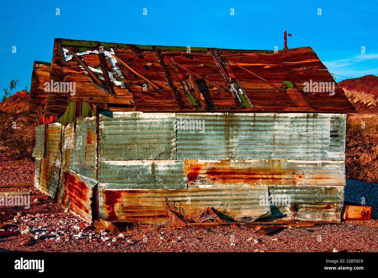 A rusted old building with a green roof. The roof is missing some ...