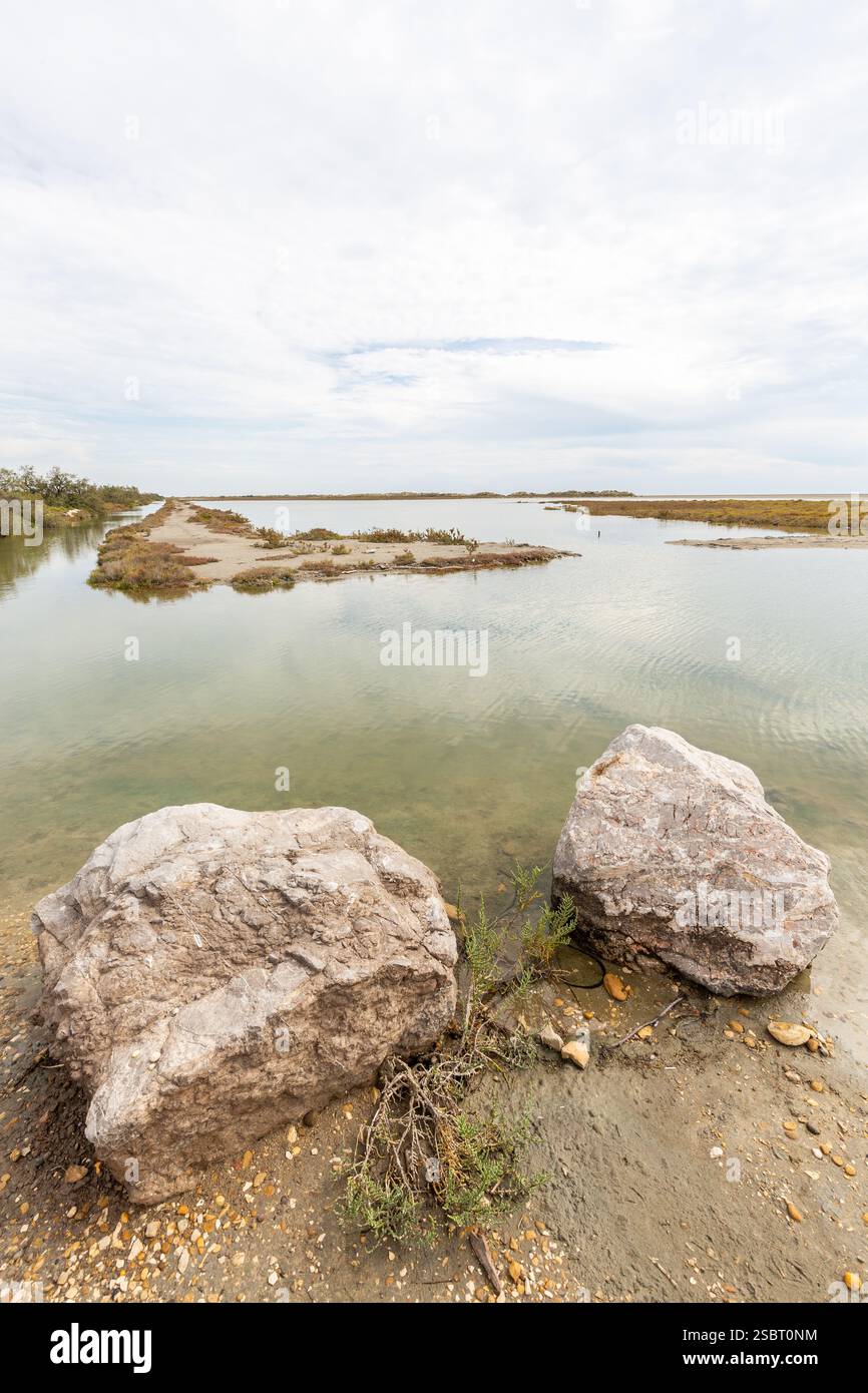 Salt water body in the Camargue plain, rock blocks in the foreground ...