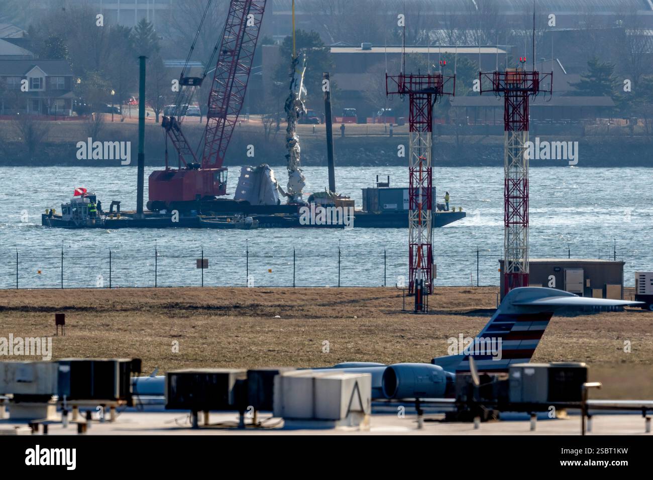 A piece of wreckage is lifted from the water onto a salvage vessel near ...