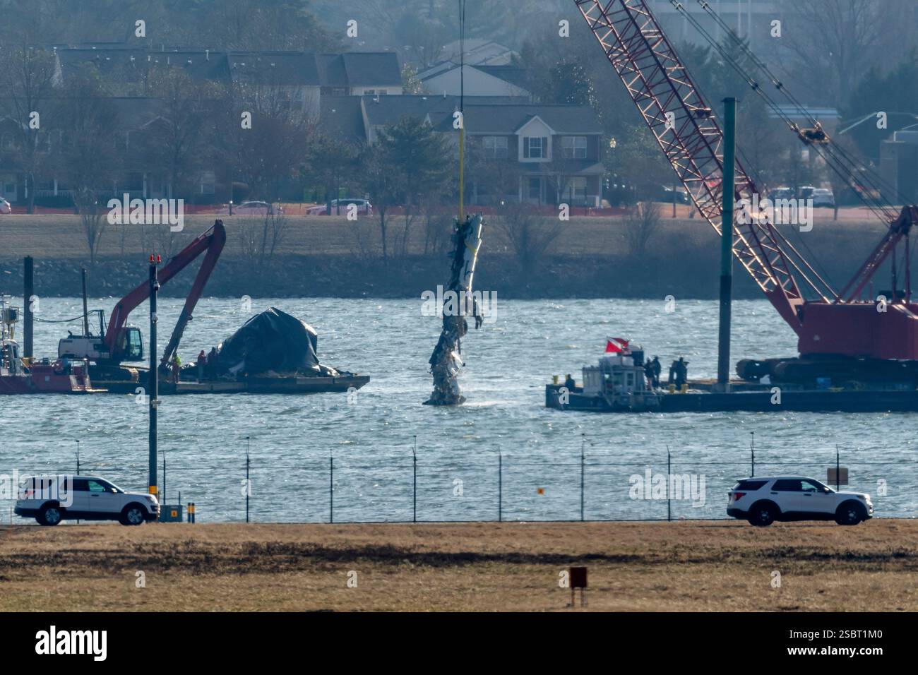 A piece of wreckage is lifted from the water onto a salvage vessel near ...