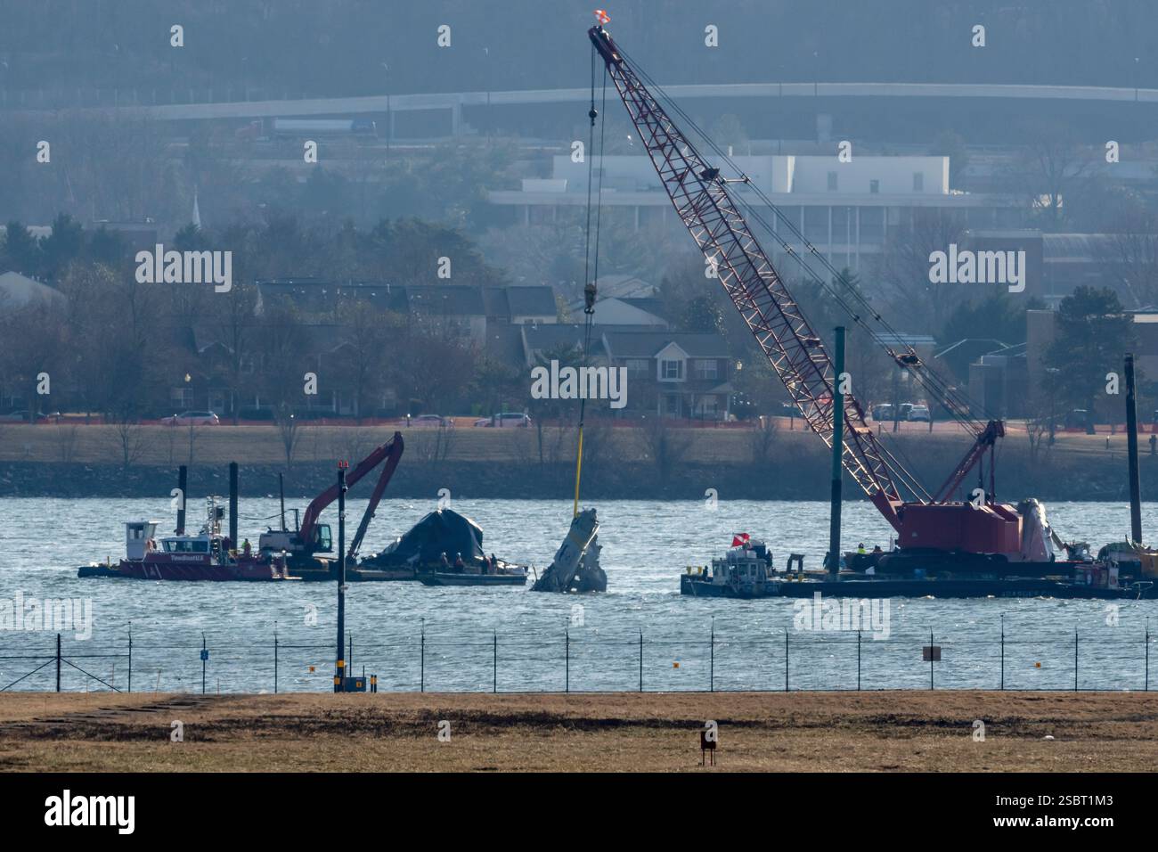 A piece of wreckage is lifted from the water onto a salvage vessel near ...