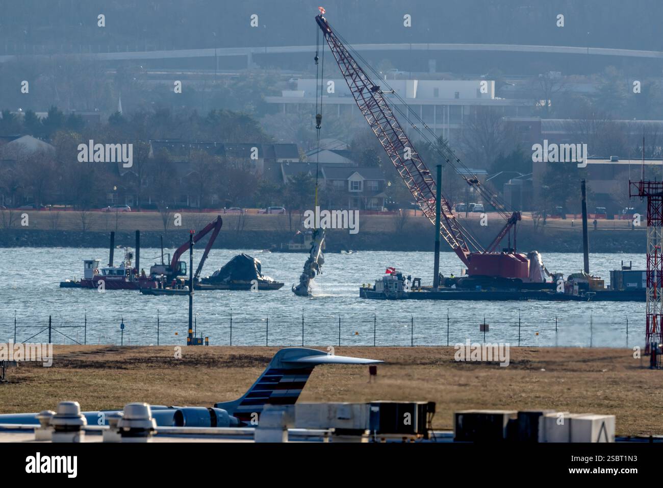 A piece of wreckage is lifted from the water onto a salvage vessel near ...