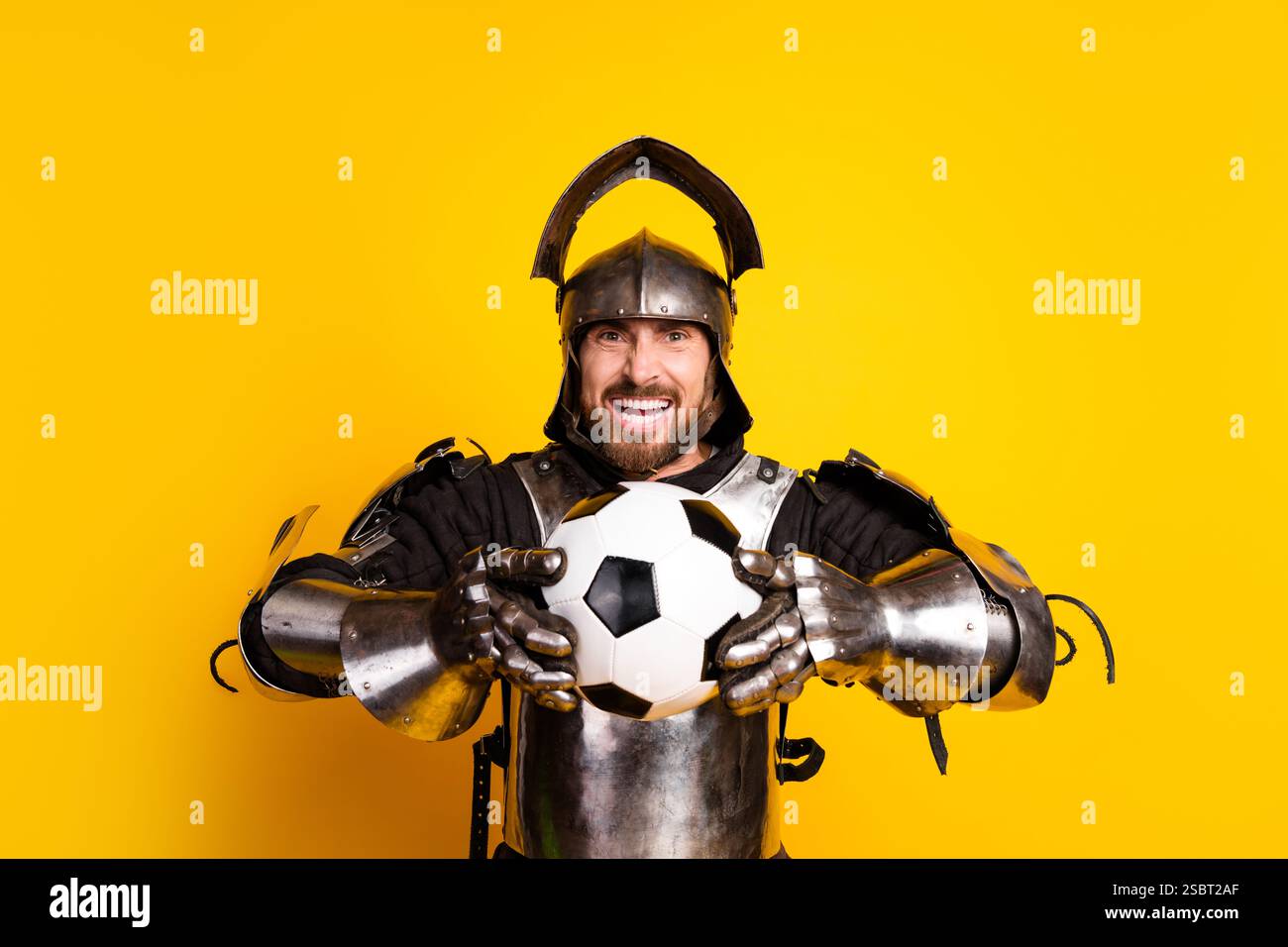 Knightly figure in medieval armor with a soccer ball against a bright ...