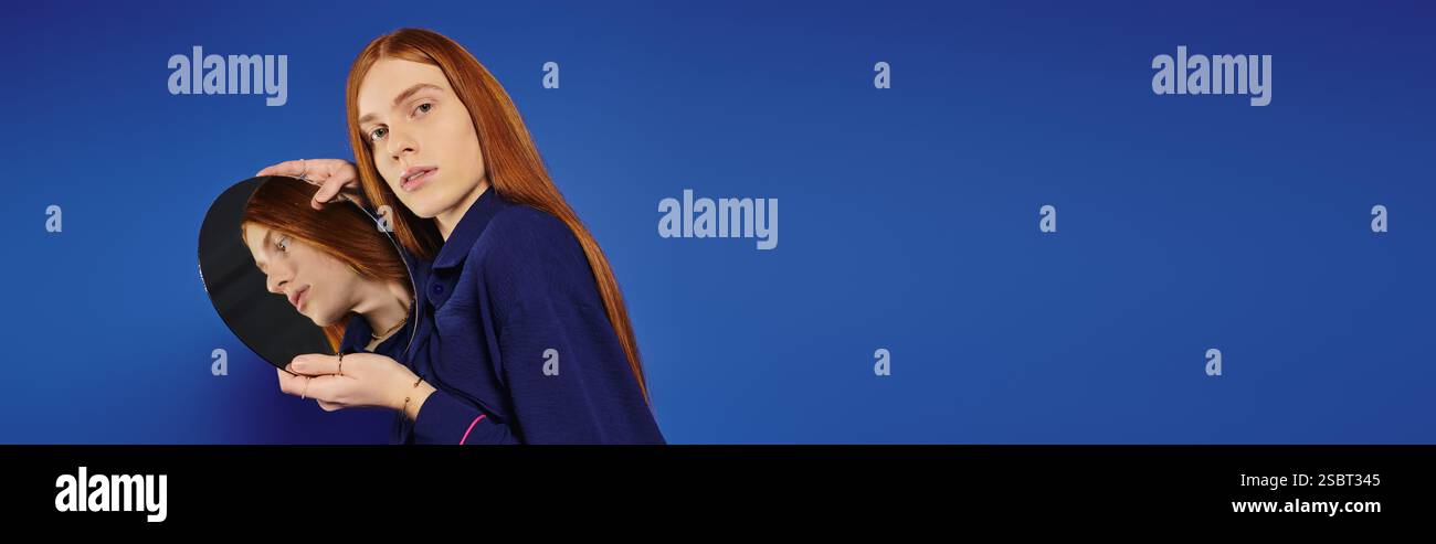Young queer man showcases his long red hair and fashion sense against a ...
