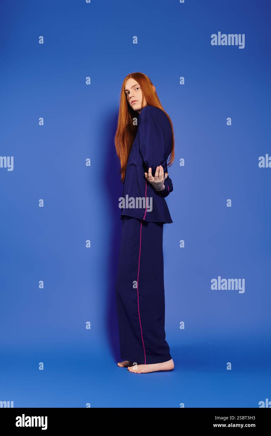 A handsome young man with long red hair strikes a fashionable pose on a ...