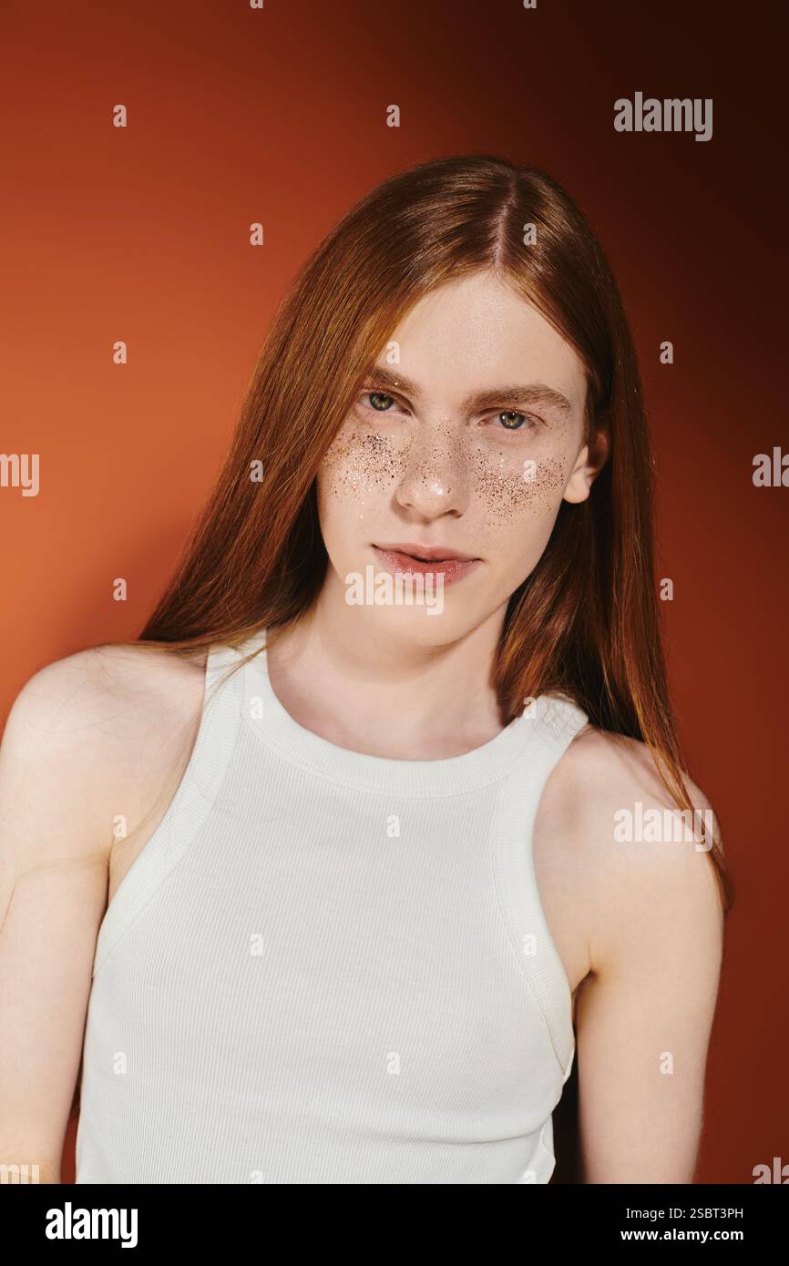 A young queer man with long red hair showcases his stylish look against ...