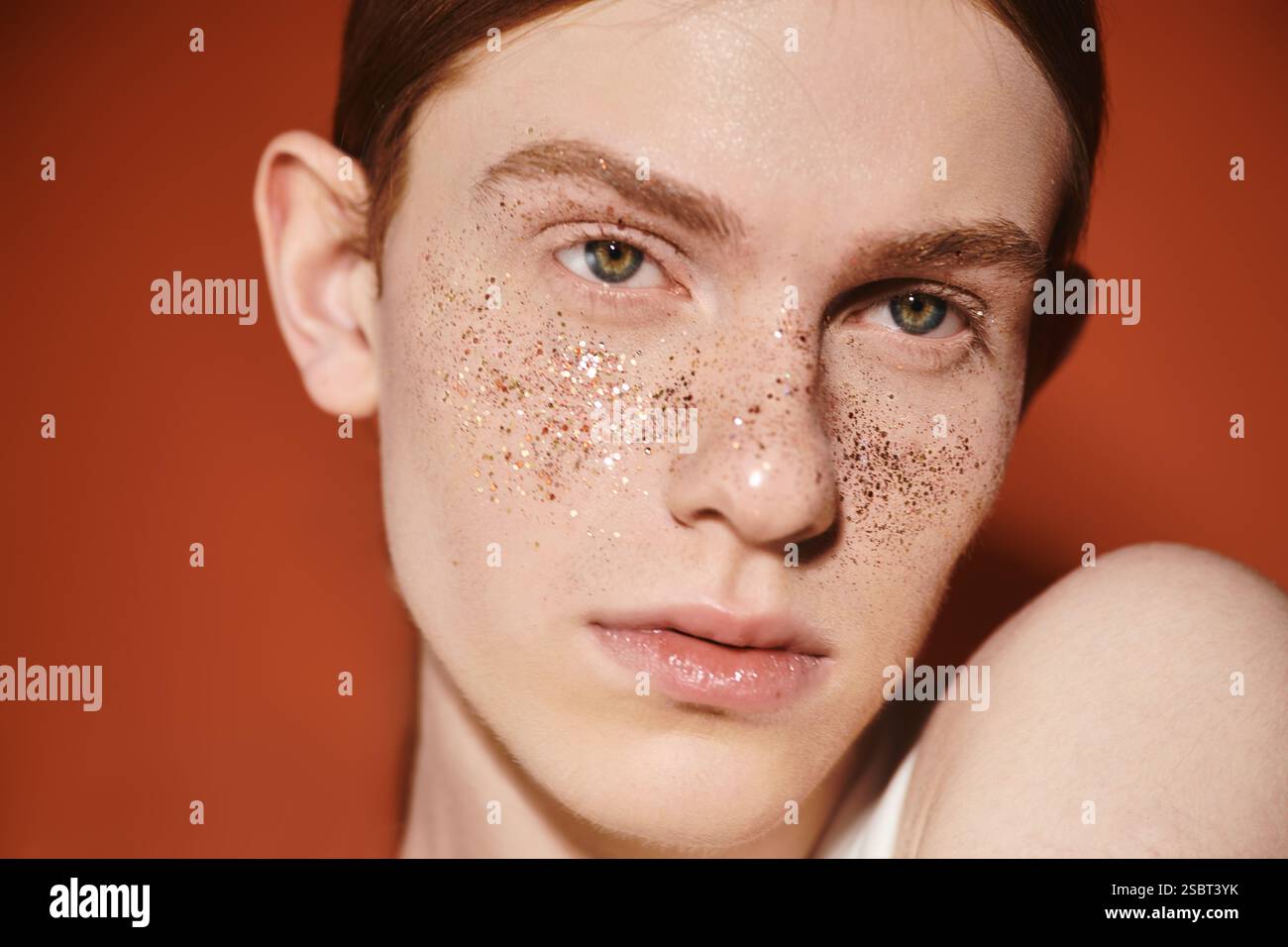 A young man with red hair shows off a stylish look, with glitter on his ...
