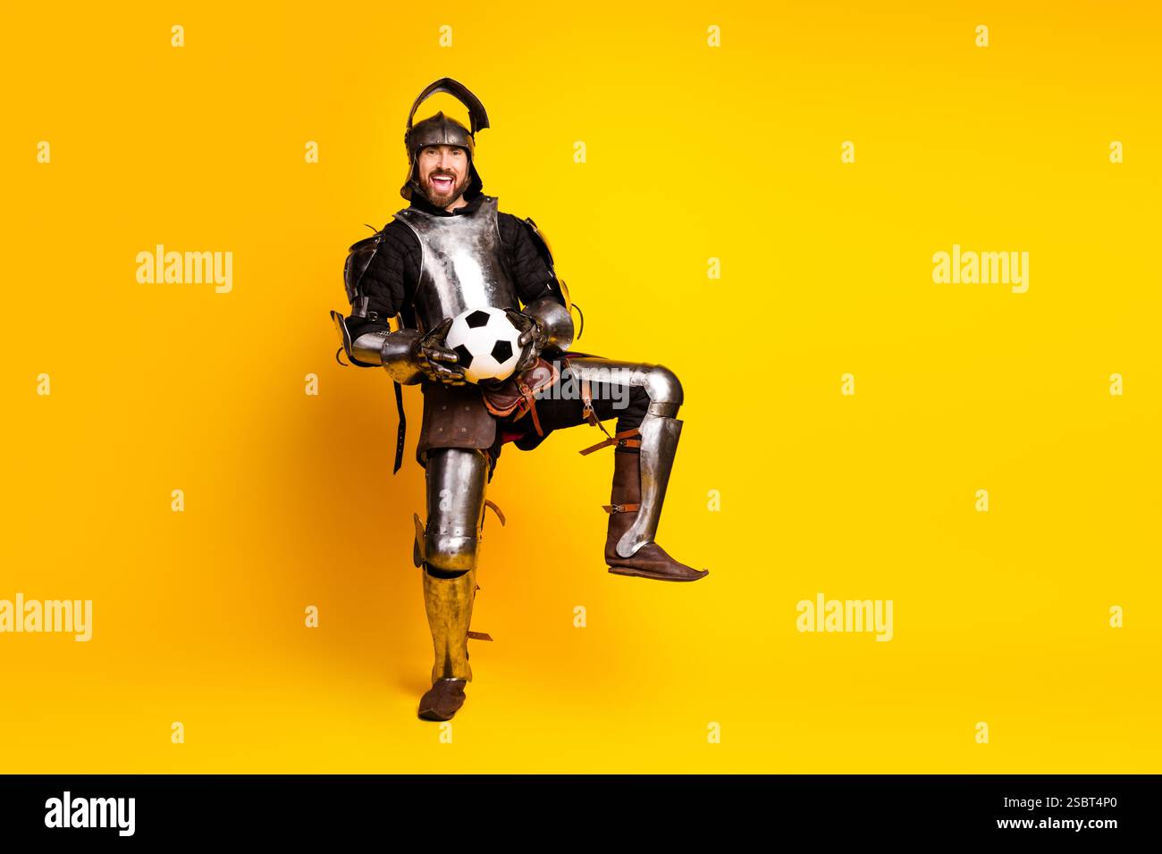 Medieval Knight in Full Armour Holding Soccer Ball on Vibrant Yellow ...