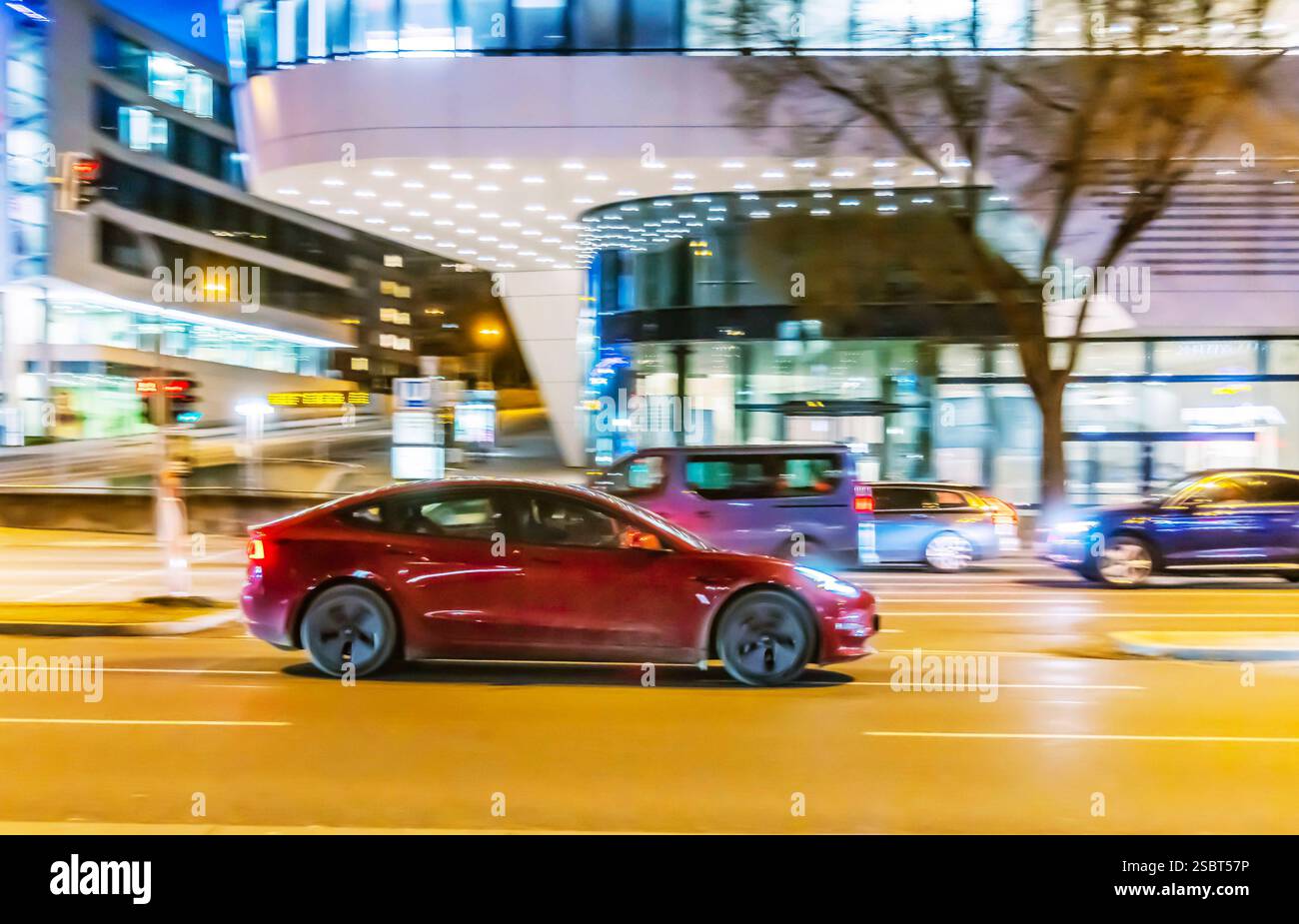 Tesla bei Nacht vor urbaner Umgebung mit moderner Architektur ...