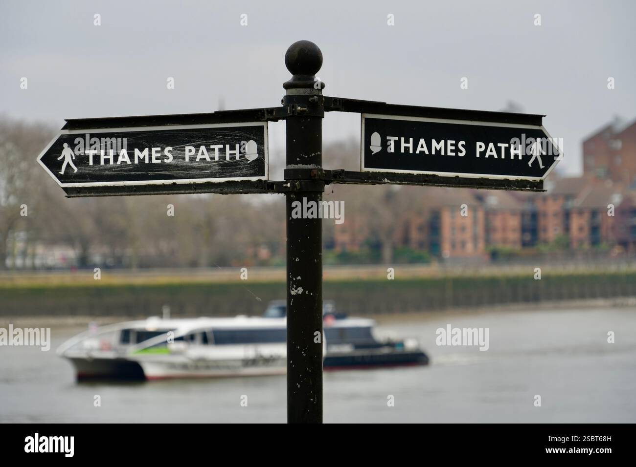 Direction sign for The Thames Path on The River Thames with a riverboat ...