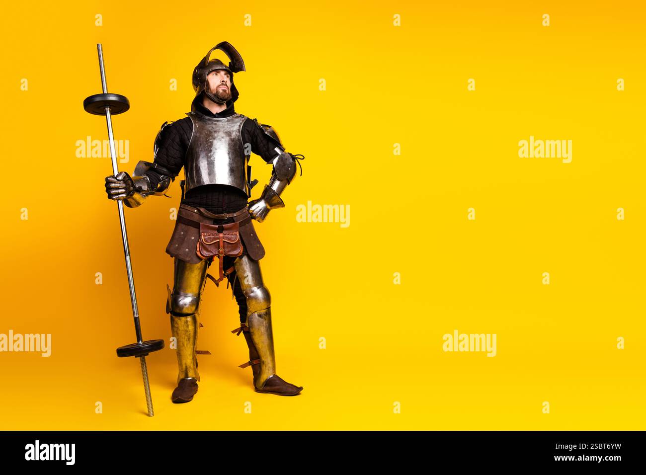 Medieval knight in full armor holding modern gym equipment against ...