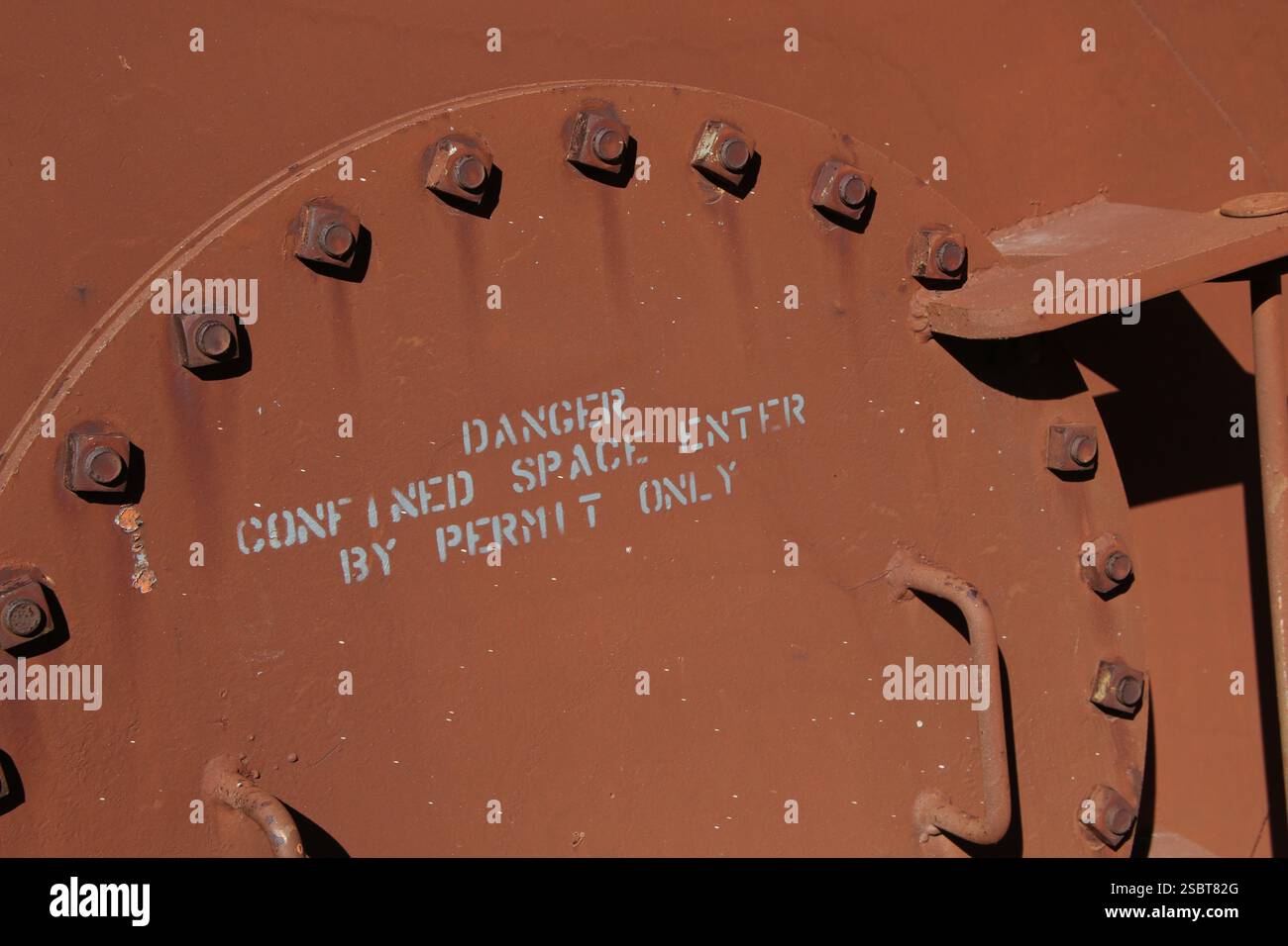 A round hatch to gain access to a steel tank with a danger warning ...