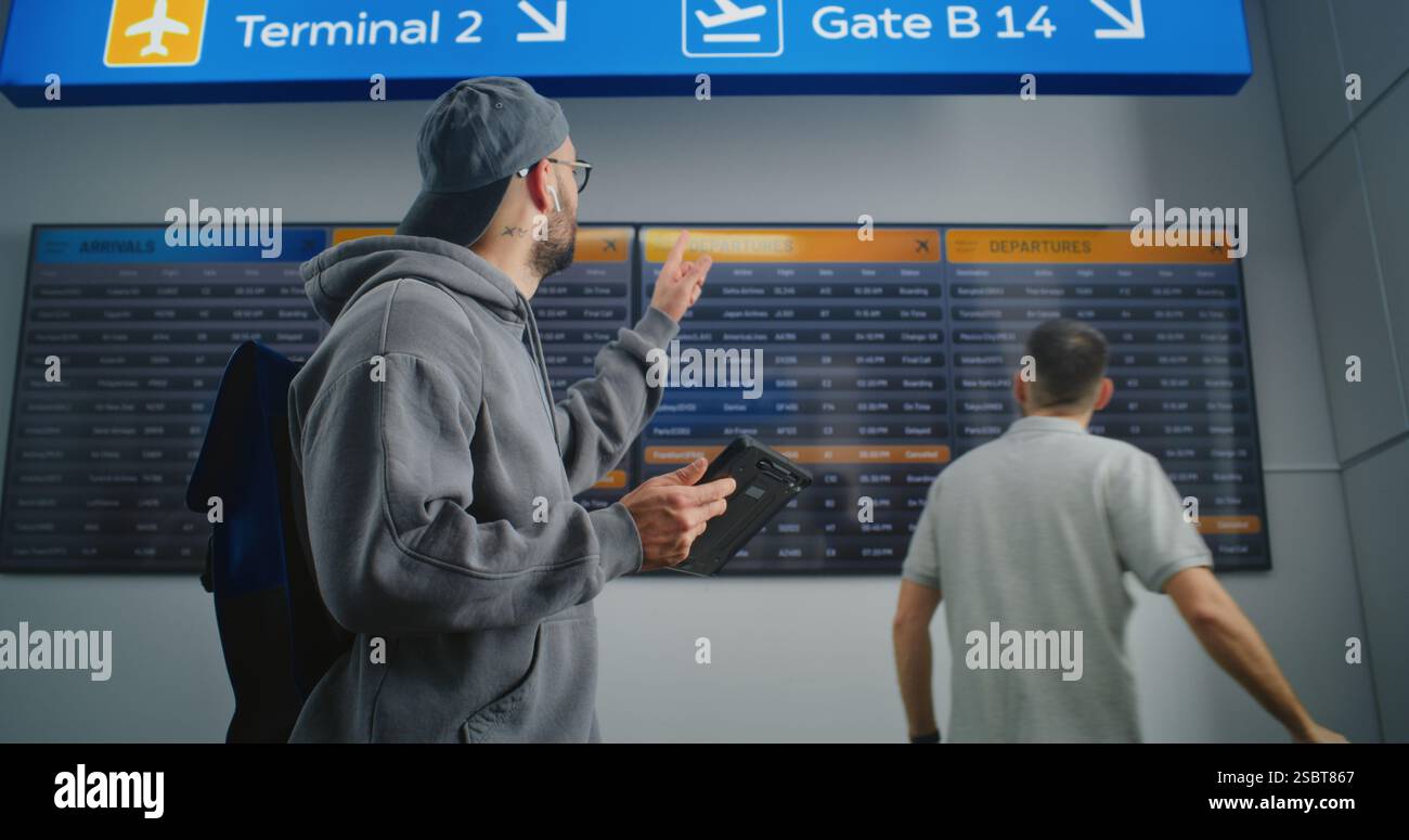 Busy Airport Terminal: Traveler with Backpack Uses Tablet Computer ...