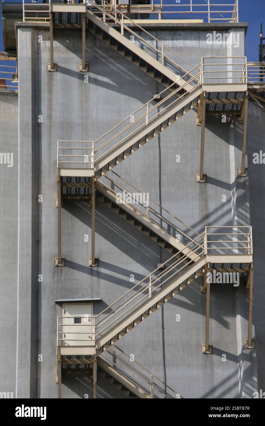 Metal stairs zig zag up and down the outside of an industrial building ...