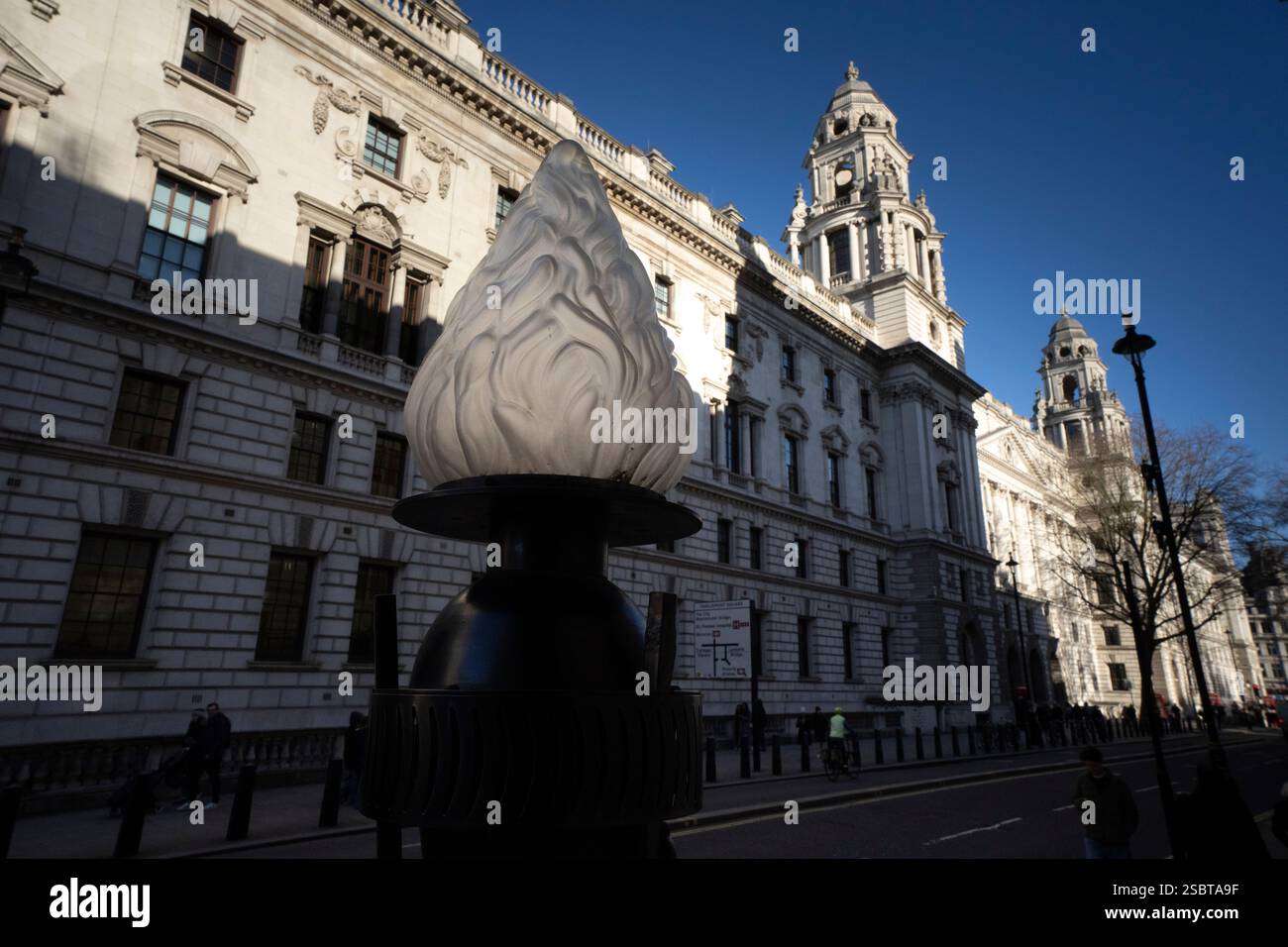 A sculpted flame monument stands before a grand London building ...