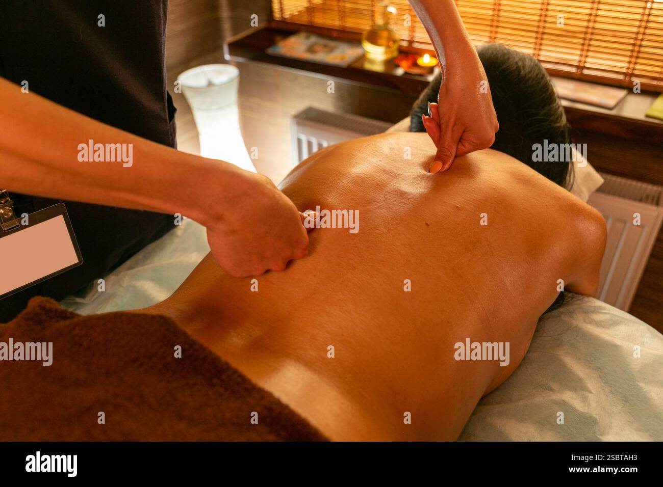 A female masseur massages a woman's back and neck. Female enjoying ...