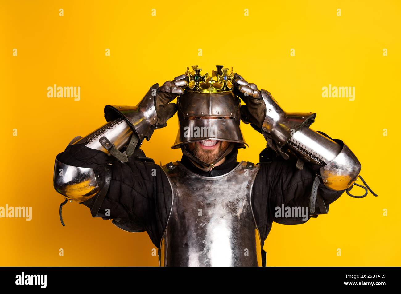 Young armored man in medieval knight costume with crown on bright ...