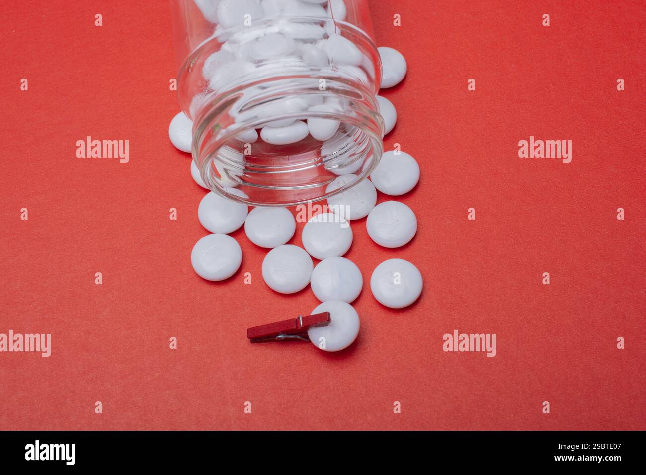 White medical pills spilling out of pills bottle, red background ...