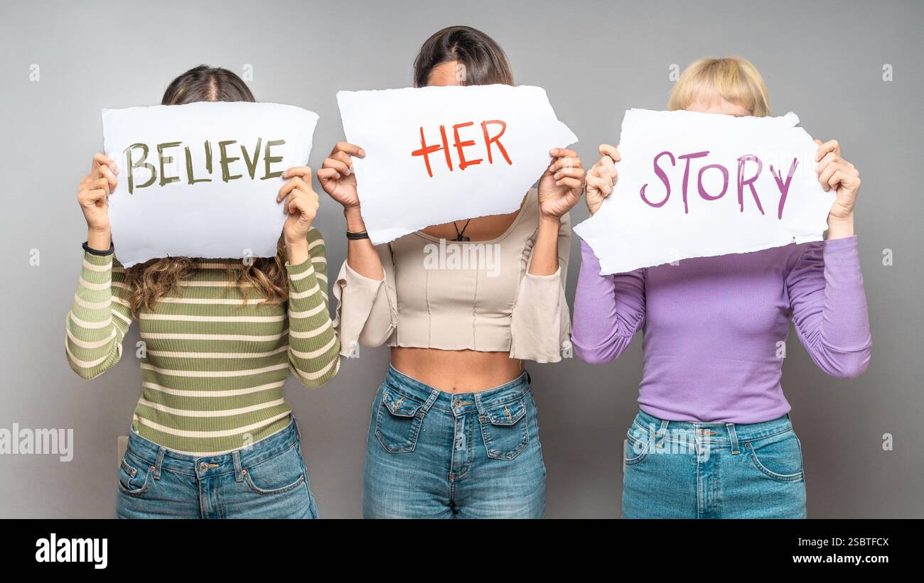 Three women holding torn paper signs that spell “Believe Her Story ...