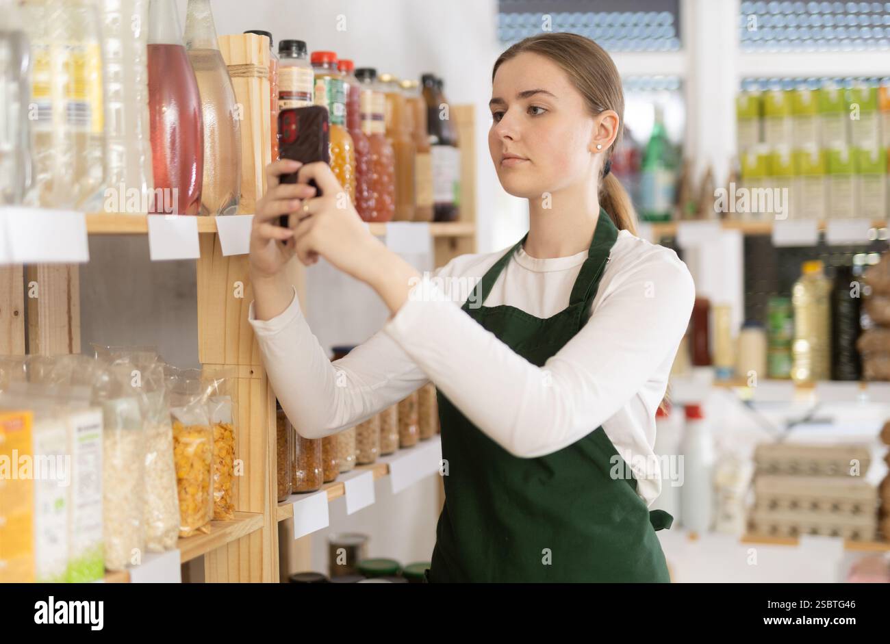 Merchandiser girl takes pictures of goods on supermarket shelves ...