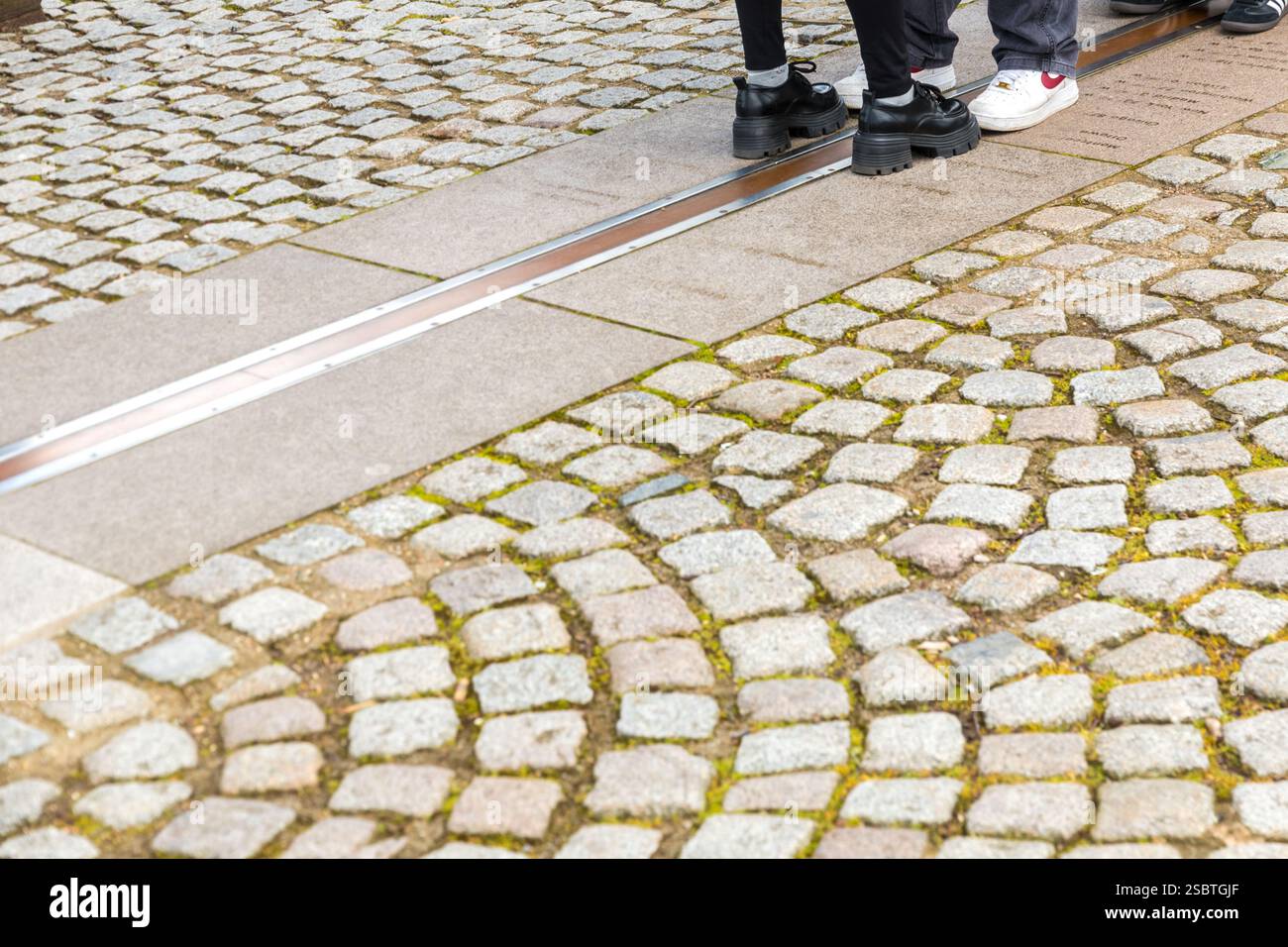Close-up view of tourists standing between the Greenwich Prime Meridian ...