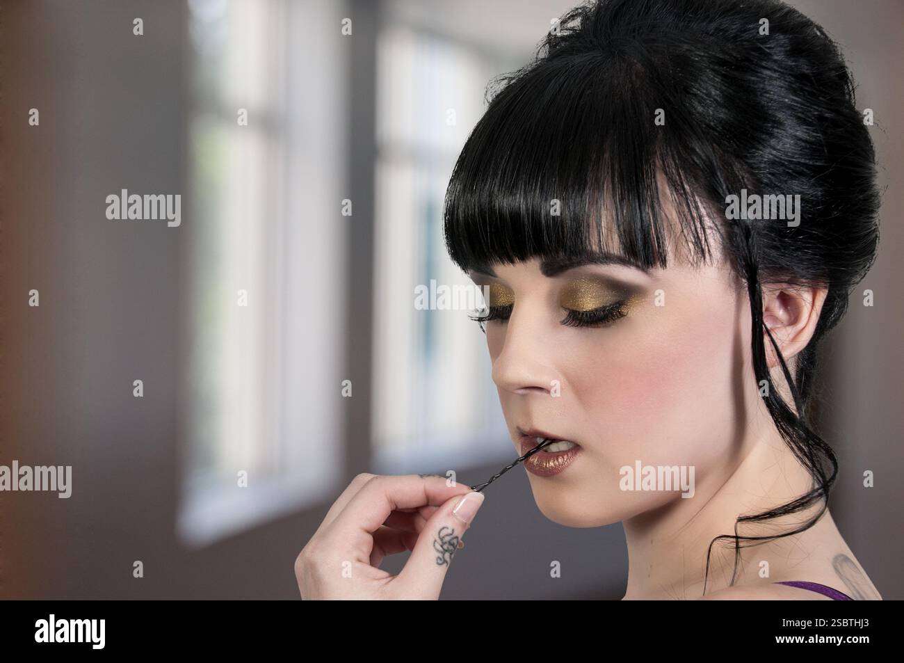 Beautiful woman biting a bobby pin before putting it into her hair ...