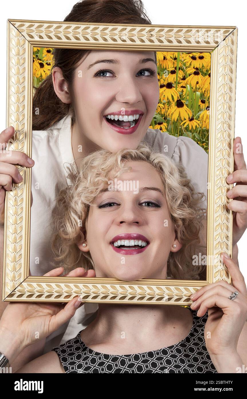 Beautiful women looking through an ornate picture frame Stock Photo - Alamy