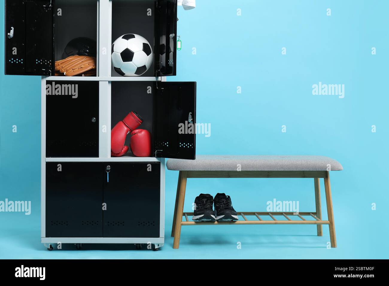 Open lockers with sport equipment, bench and sneakers on light blue ...