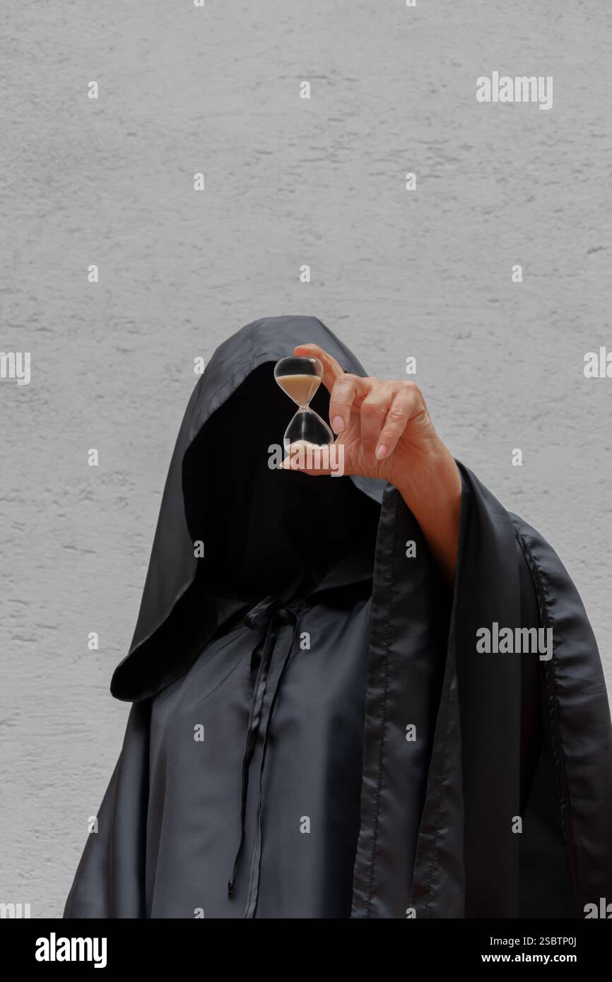 A mystical figure in a dark hood shows the passage of time Stock Photo ...
